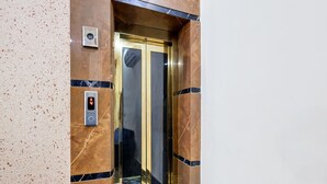 Um elevador com painel digital, paredes de mármore e carpete estampado.