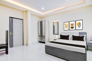 Quarto moderno com uma cama grande, um guarda-roupa, um banco e três obras de arte emolduradas na parede.