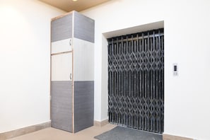 Um interior moderno com um guarda-roupa alto, um portão de metal e um tapete pequeno.