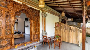 Uma entrada de madeira ricamente esculpida, com um banco, uma cadeira e uma pequena mesa com uma planta.