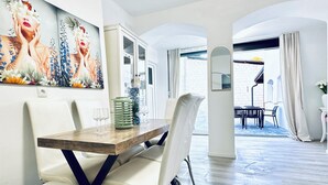 Uma sala de jantar com mesa de madeira, cadeiras brancas e uma grande pintura floral na parede.