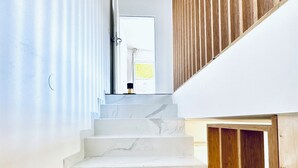 Uma escadaria com degraus de mármore branco que levam a um corrimão de madeira.