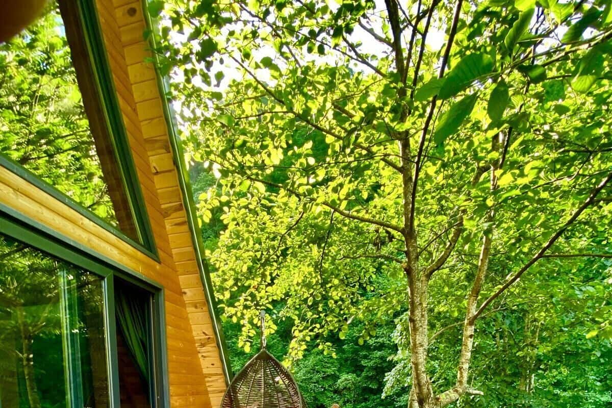 Um deck de madeira com uma mesa e cadeiras, com vista para uma floresta verdejante e uma cachoeira.