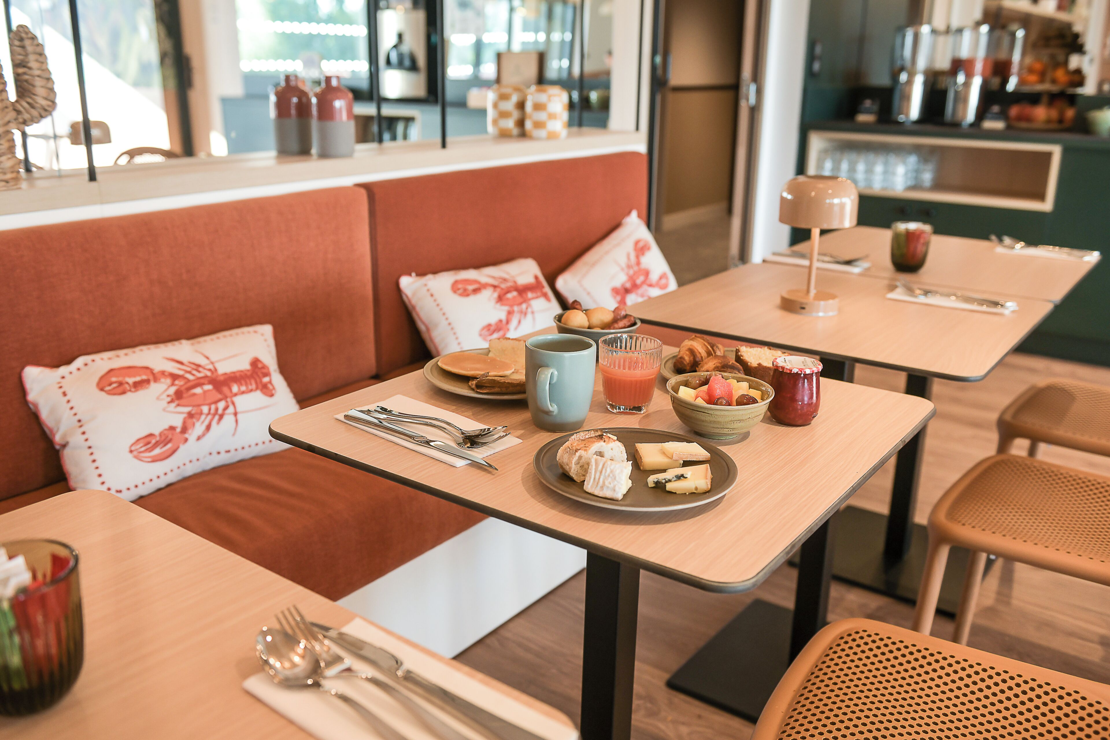 Um restaurante com área de cabines, uma mesa com itens de café da manhã e um canto para café.