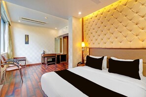 Quarto de hotel com uma cama grande, uma mesa, uma cadeira e um espelho.