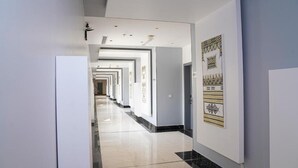 Um corredor com várias portas, luminárias e decorações padronizadas nas paredes.