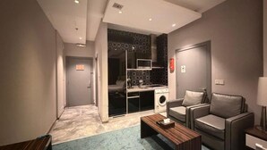 Um espaço compacto com cozinha compacta, sofá, mesa de centro e televisão.