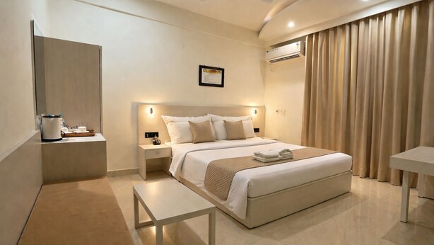 Quarto de hotel com uma cama grande, mesas de cabeceira, escrivaninha e ventilador de teto.