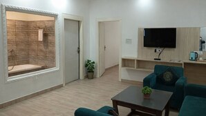 Uma sala de estar moderna com sofás verde-água, uma mesa de centro, uma televisão e um chuveiro com divisória de vidro.