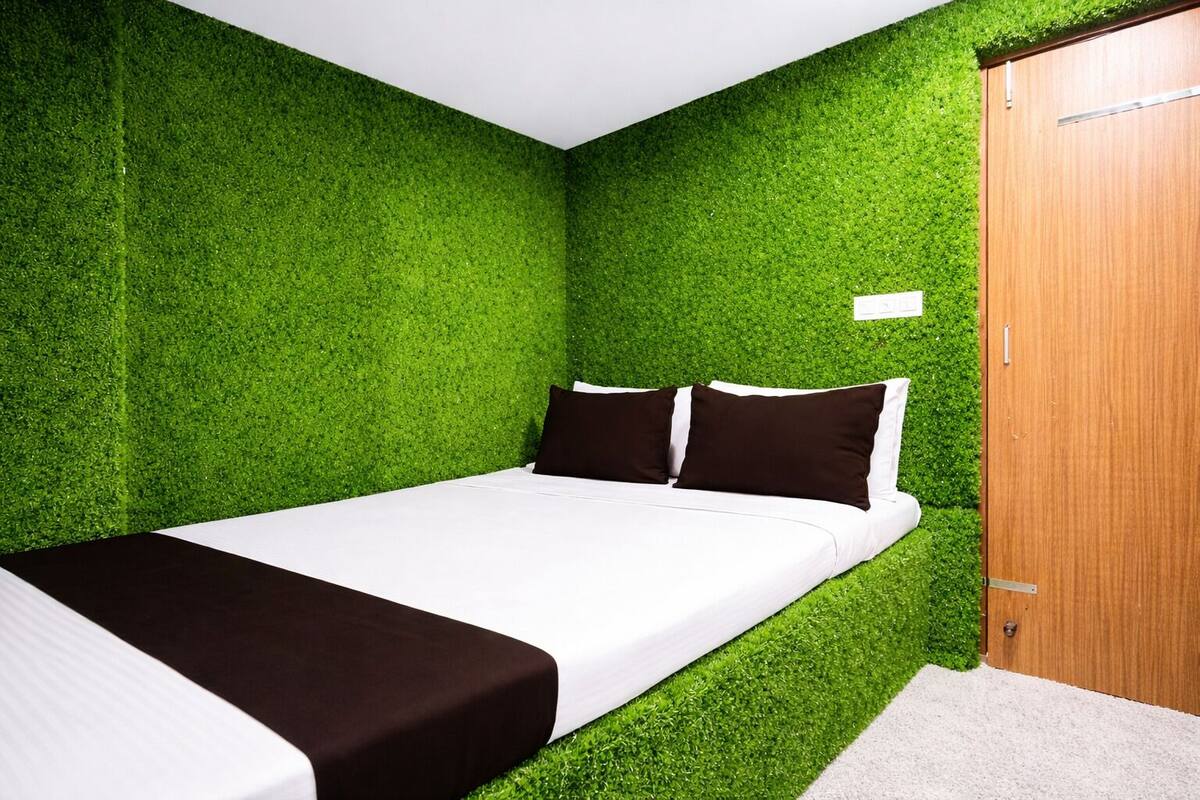 Quarto com cama, parede verde e porta de madeira.