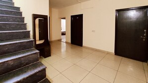 Um corredor com escada, duas portas e piso de azulejos.