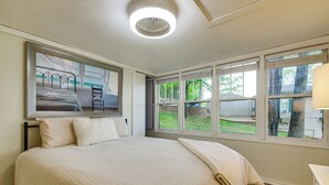 Quarto com cama grande, várias janelas e vista para o exterior.