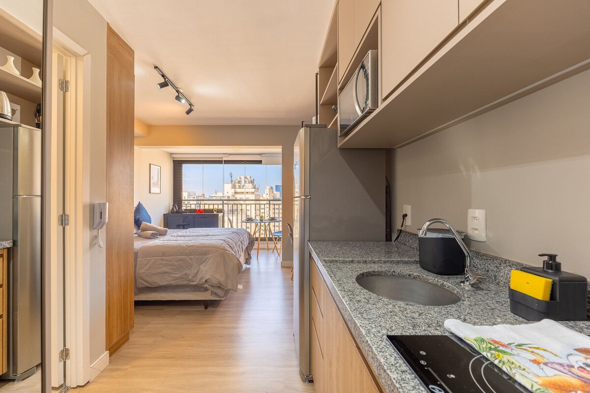 Quarto de hotel compacto com cozinha compacta, uma cama e vista para a paisagem urbana.