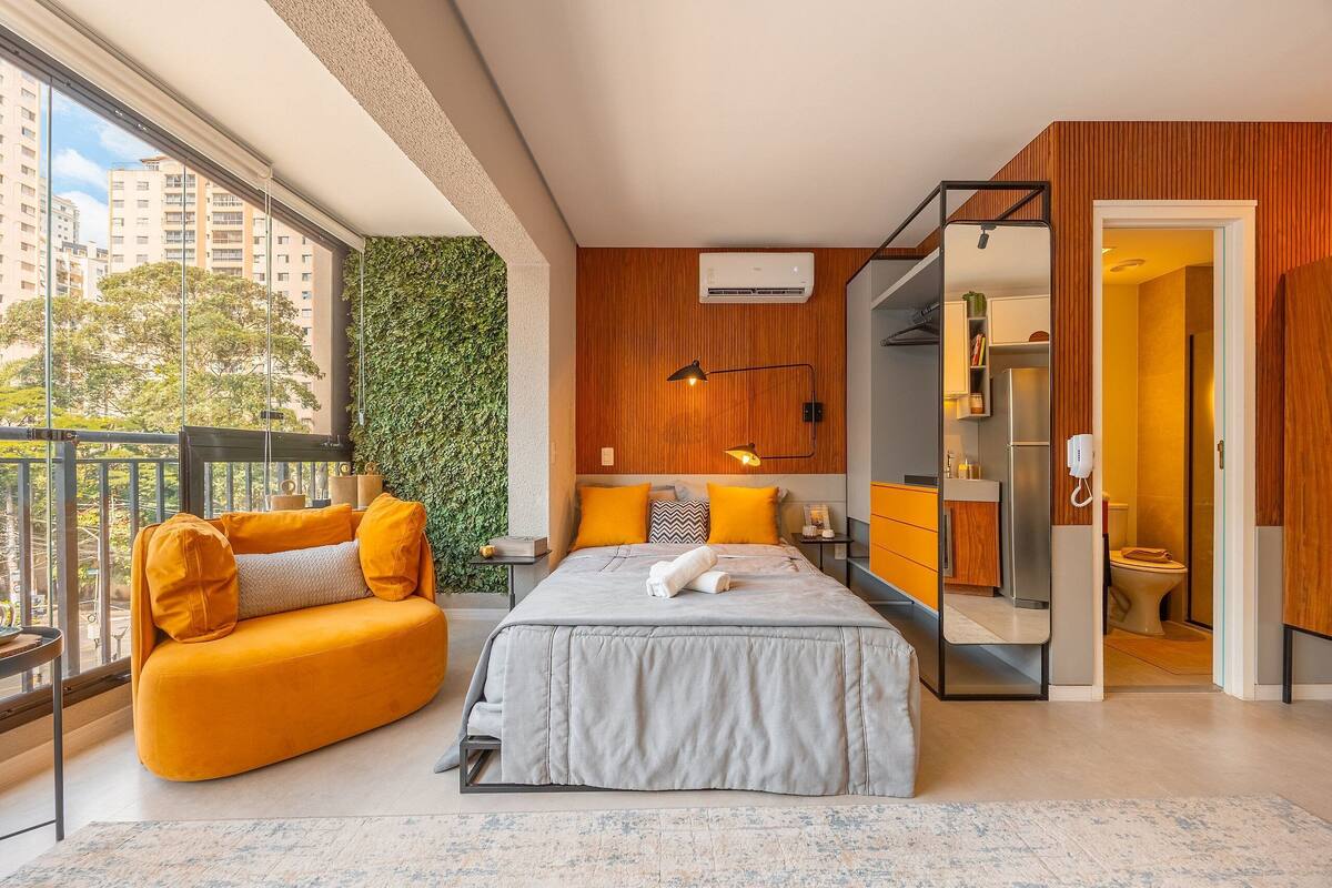 Quarto moderno com cama, sofá, banheiro e vista para a cidade.