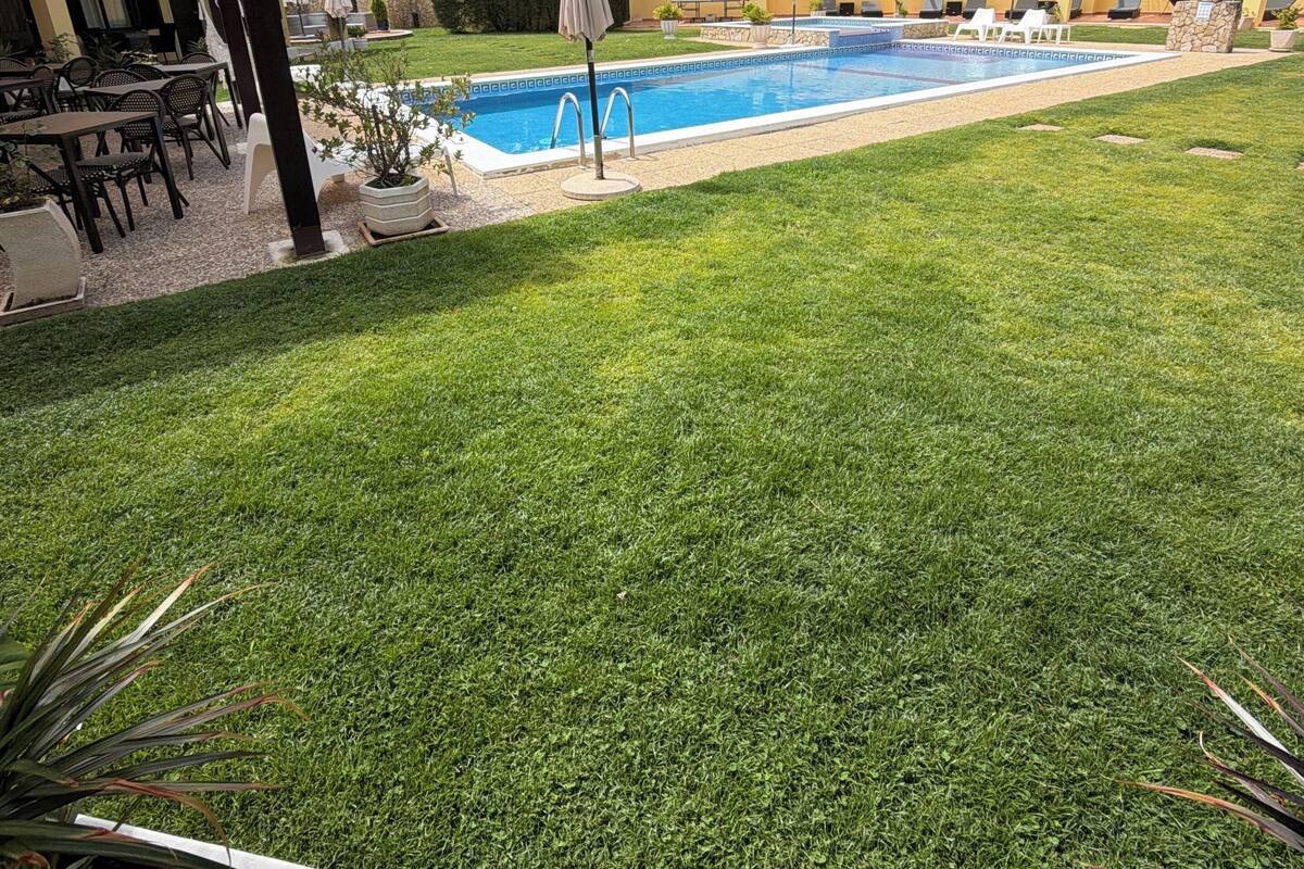 Um quintal com piscina, área de estar externa e varanda coberta.