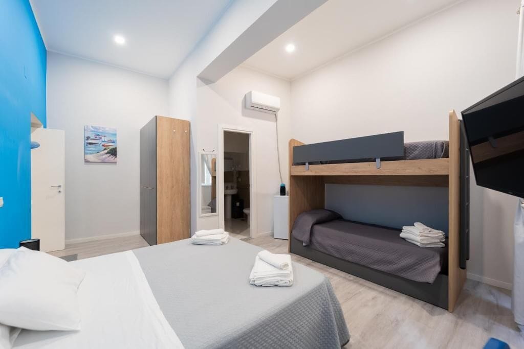 Quarto de hotel moderno com uma cama de solteiro, uma cama individual, um guarda-roupa e uma televisão.