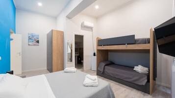 Quarto de hotel moderno com uma cama de solteiro, uma cama individual, um guarda-roupa e uma televisão.