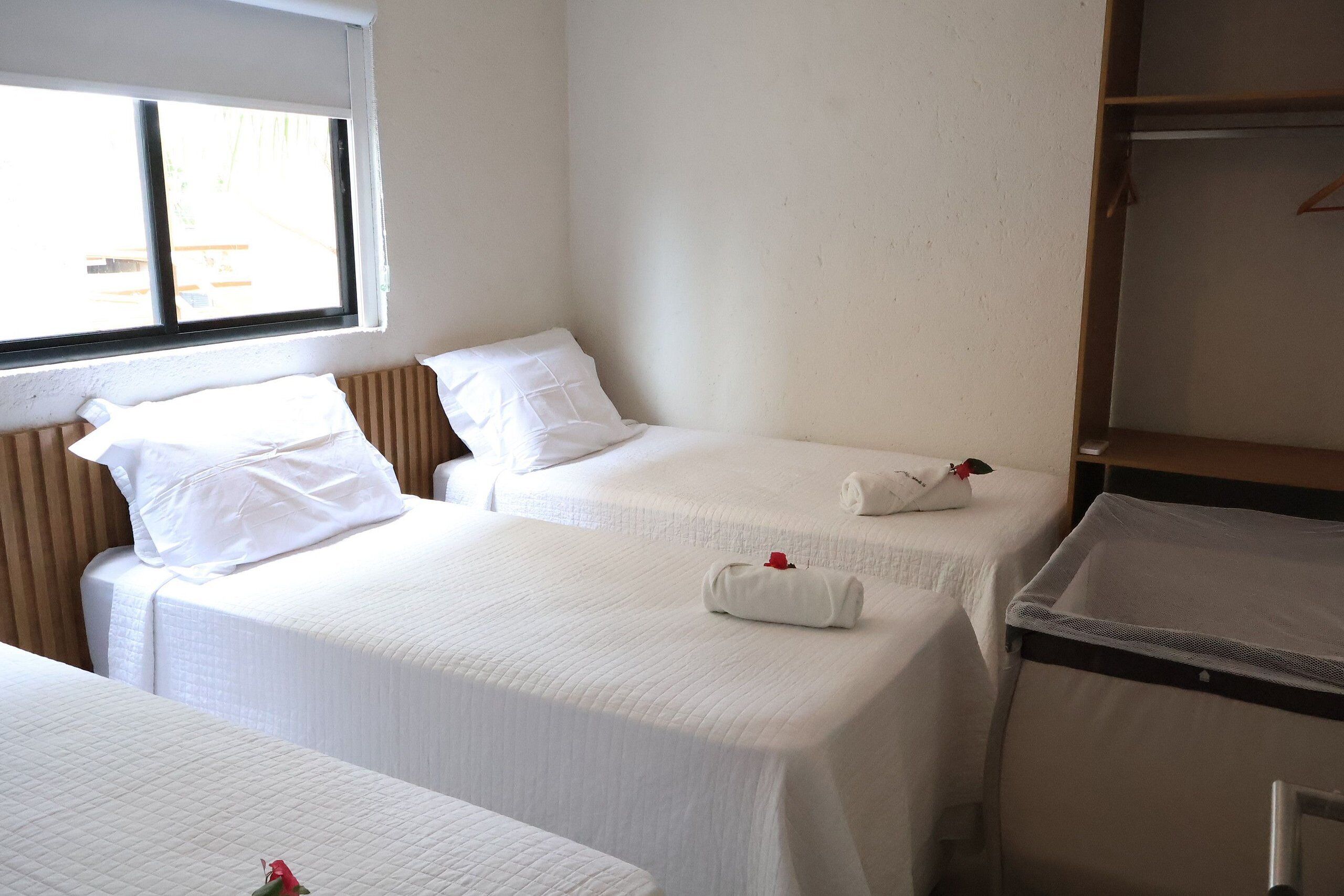 Quarto de hotel com duas camas, uma janela e um guarda-roupa.