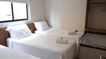 Quarto de hotel com duas camas, uma janela e um guarda-roupa.