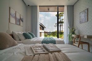 Quarto com cama grande, escrivaninha e vista para o exterior.