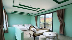 Quarto de hotel com sofá, duas camas, varanda e área de jantar.