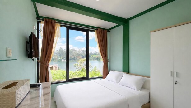 Quarto com cama, guarda-roupa, televisão e janela com cortinas.