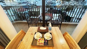 Varanda com mesa posta para dois, cadeiras, uma garrafa de água e duas xícaras de café.