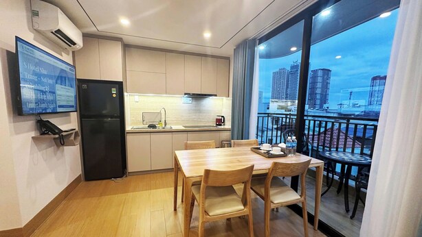 Quarto de hotel compacto com cozinha compacta, área de refeições e varanda com vista para a cidade.