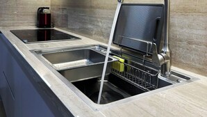 Uma cozinha moderna com eletrodomésticos de aço inoxidável, lava-louças embutida e um recurso de água.