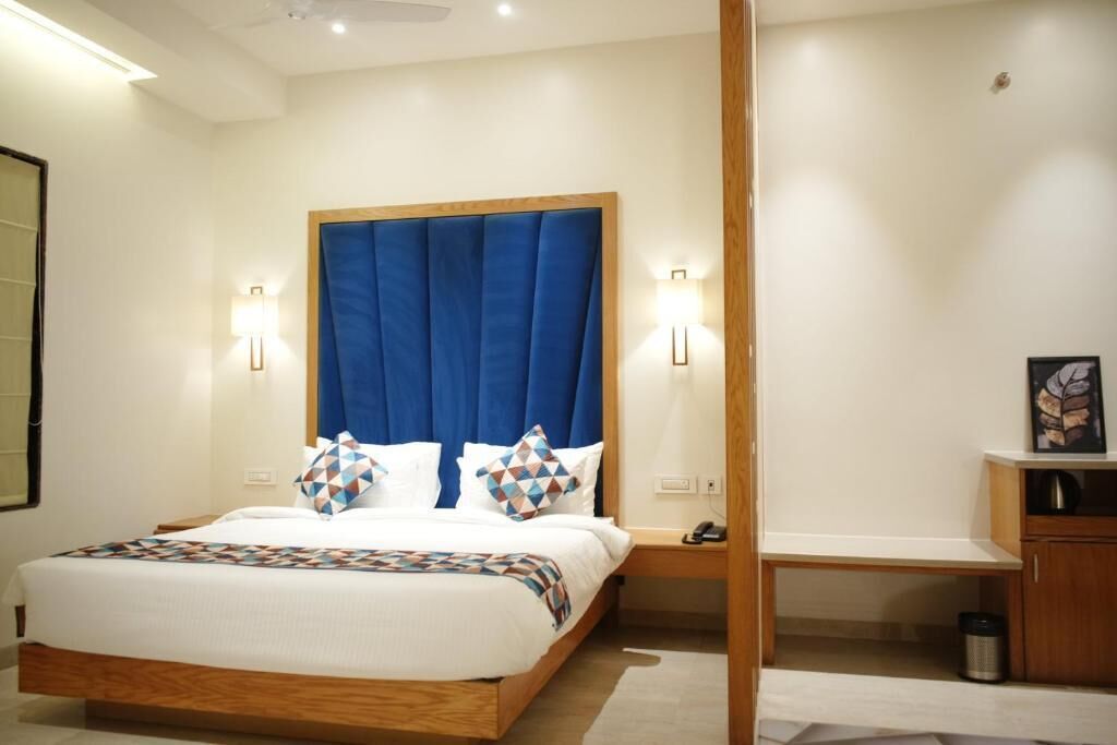 Quarto de hotel moderno com uma cama grande, duas luminárias de cabeceira, uma mesa de cabeceira de madeira e um pequeno armário.
