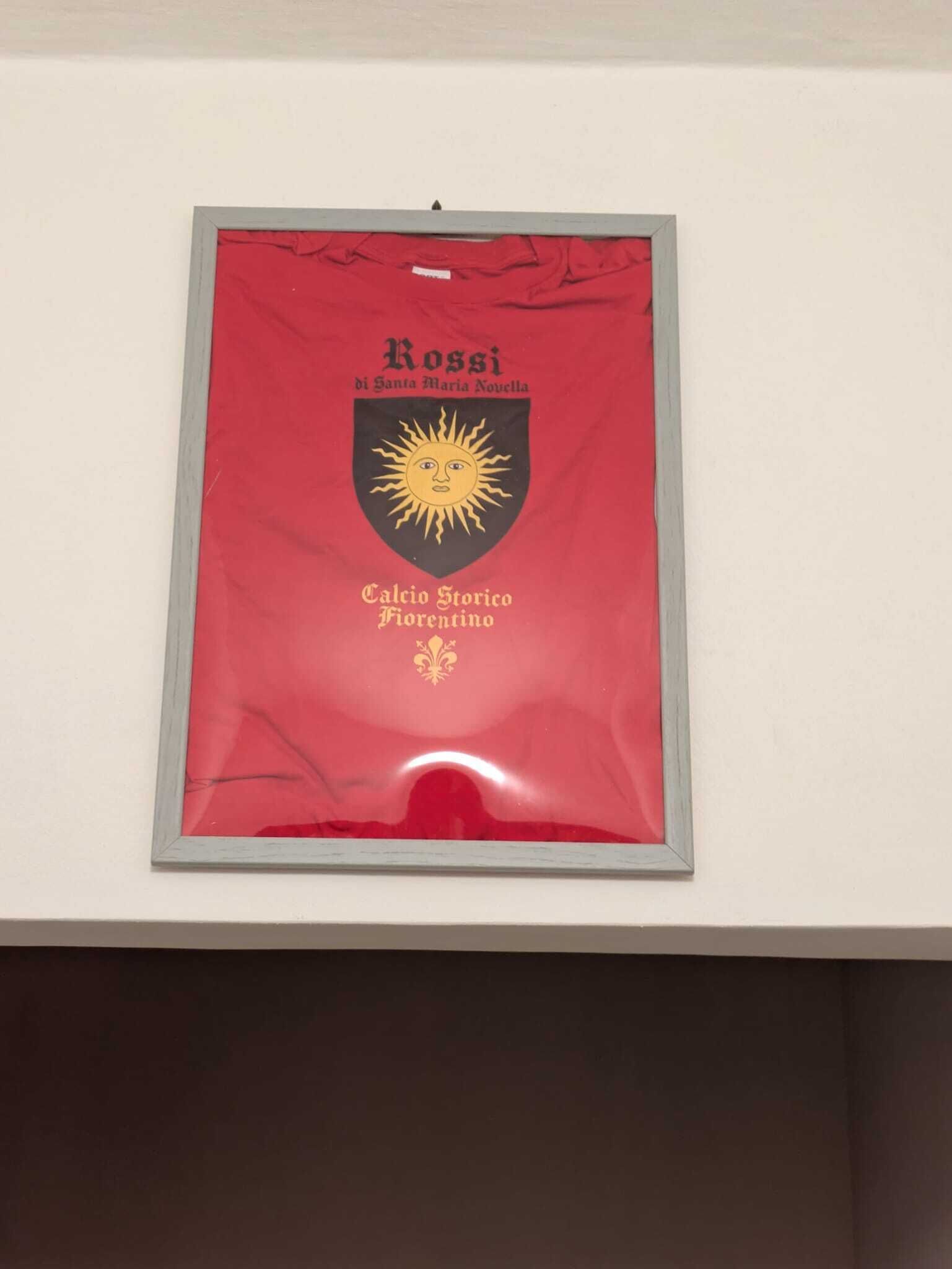 Um certificado ou prêmio emoldurado, com fundo vermelho e letras douradas.