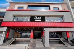 Um edifício moderno com um destaque para o letreiro 'Collection', uma escadaria que leva à entrada e um toldo vermelho.