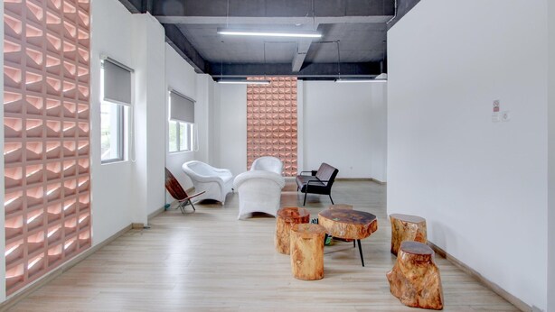 Um interior moderno com piso de madeira, paredes brancas, parede com padrão geométrico e várias áreas de estar.