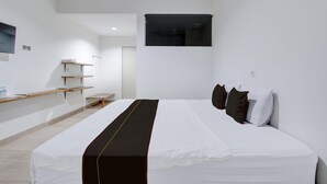 Quarto de hotel moderno com uma cama grande, televisão de tela plana na parede e design minimalista.