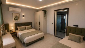 Quarto de hotel com uma cama grande, uma cama menor, um guarda-roupa, um espelho e um aparelho de ar condicionado.