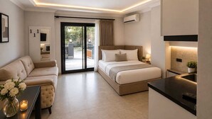 Quarto de hotel moderno com cama, sofá, pequeno-almoço e porta de correr de vidro para o exterior.