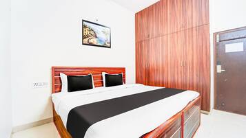 Quarto com cama, guarda-roupa de madeira e um quadro na parede.
