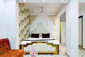 Quarto com cama grande, ventilador de teto e decoração na parede.