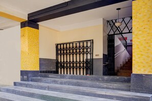 Escadaria levando a um portão com parede estampada e teto com vigas aparentes.