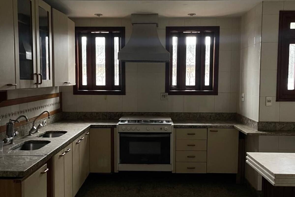 Cozinha equipada com fogão, forno, duas pias e uma janela com grade decorativa.
