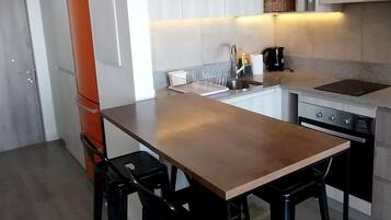 Uma cozinha moderna com uma mesa de madeira, cadeiras pretas e um tapete listrado.