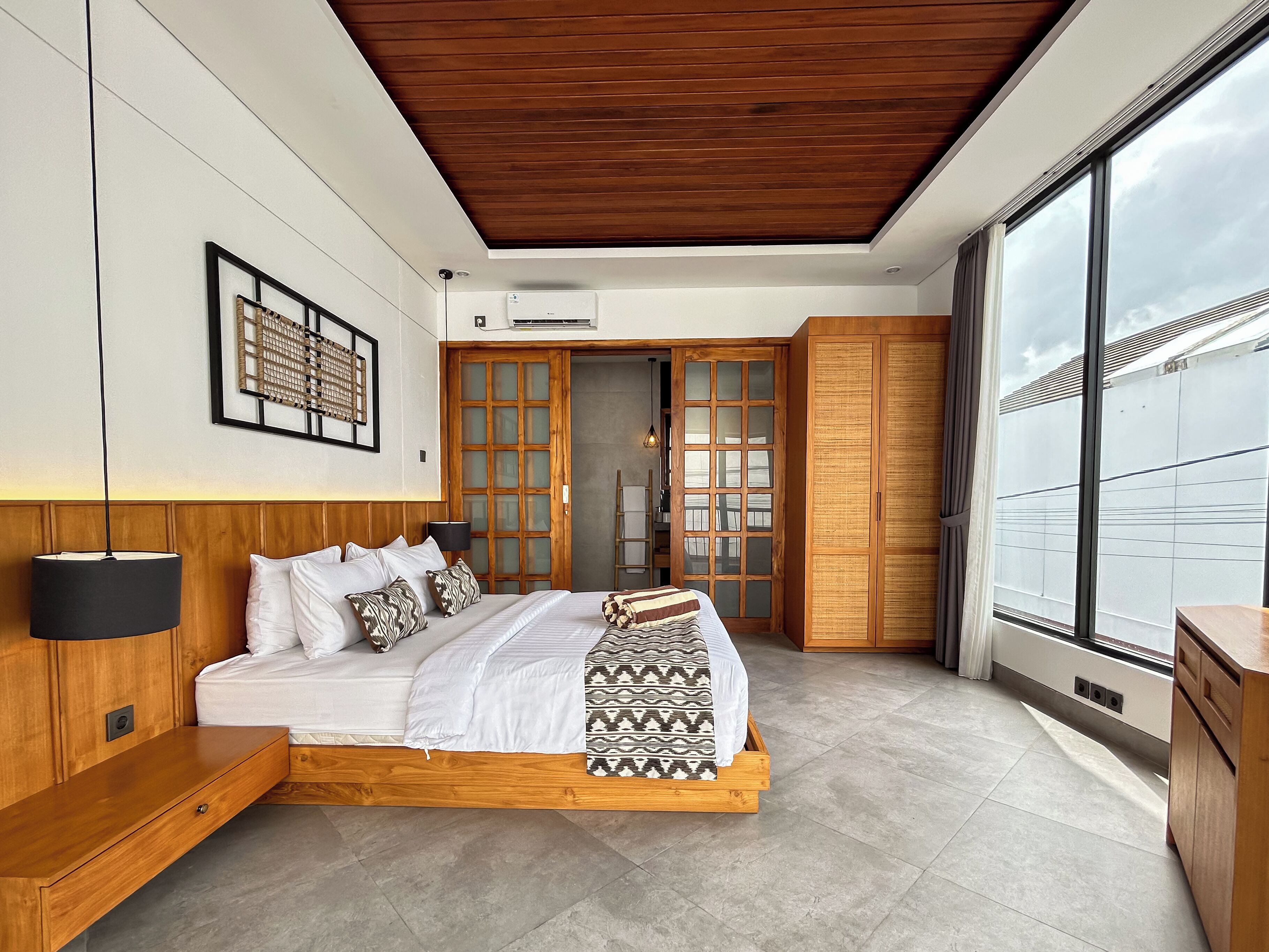Quarto moderno com cama de madeira, uma janela grande e um guarda-roupa.