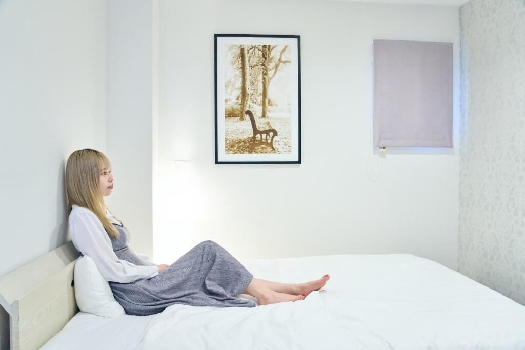 Um quarto com uma cama, um quadro na parede e uma janela com persiana.