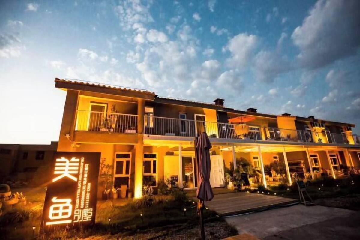 Hotel com vários andares, varandas, área de estar coberta ao ar livre e uma placa com caracteres chineses.