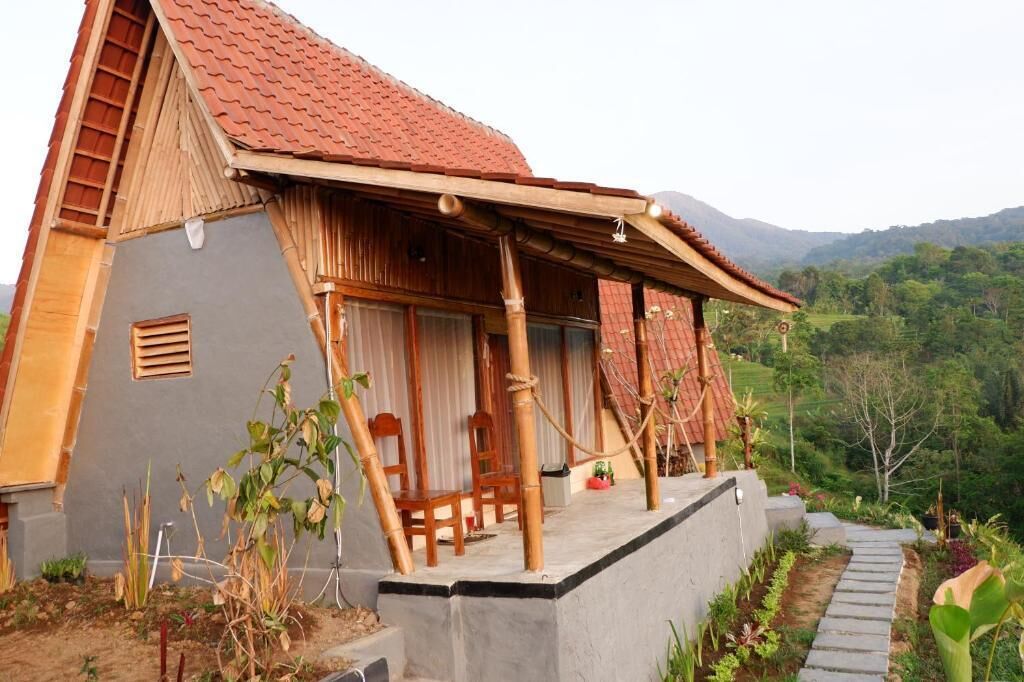 Uma casa com telhado inclinado, fachada de madeira e varanda com cadeiras.