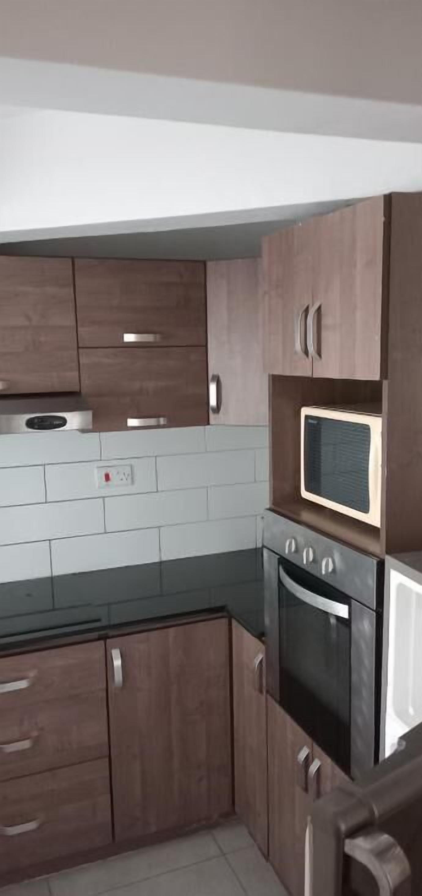 Uma cozinha com armários de madeira, micro-ondas e forno.