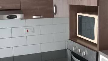 Uma cozinha com armários de madeira, micro-ondas e forno.