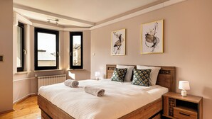 Quarto com cama de madeira, duas janelas, mesa de cabeceira e decoração na parede.