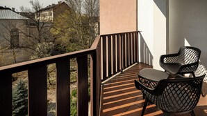 Varanda com guarda-corpo de madeira, duas cadeiras de rede pretas e vista para edifícios e árvores.
