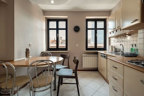 Cozinha moderna com mesa de jantar, cadeiras, um relógio e janelas.